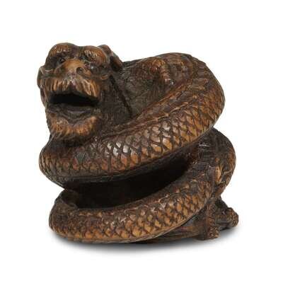 A Japanese carved wood netsuke of a coiled three clawed dragon ...